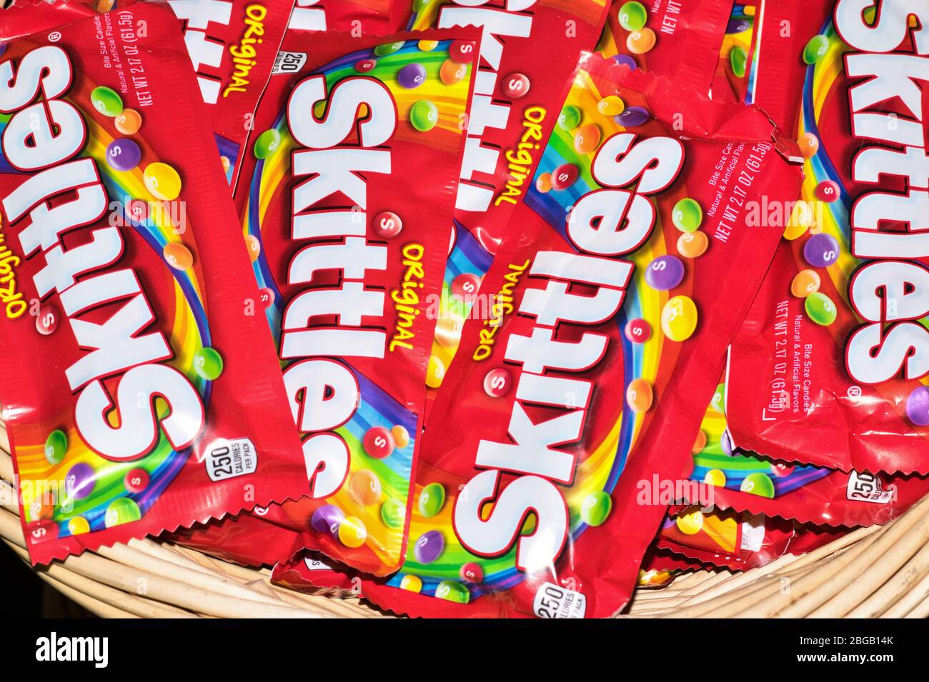 Skittles candy packets scattered loosely in a wicker basket. Hard ...