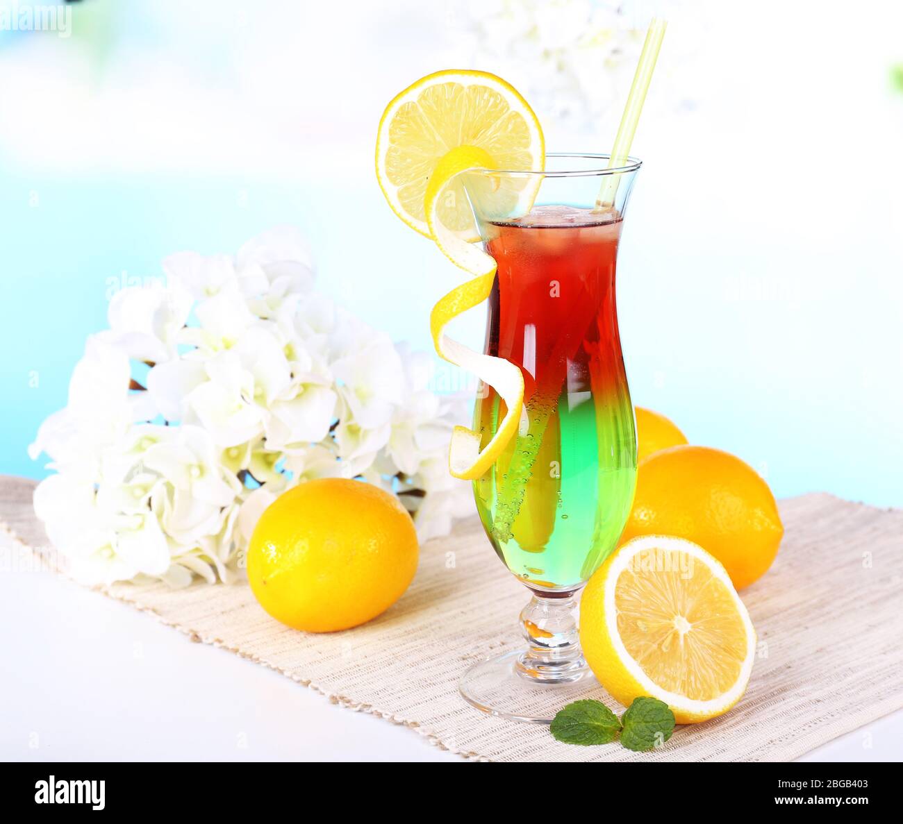 Glass of cocktail on table on light blue background Stock Photo - Alamy