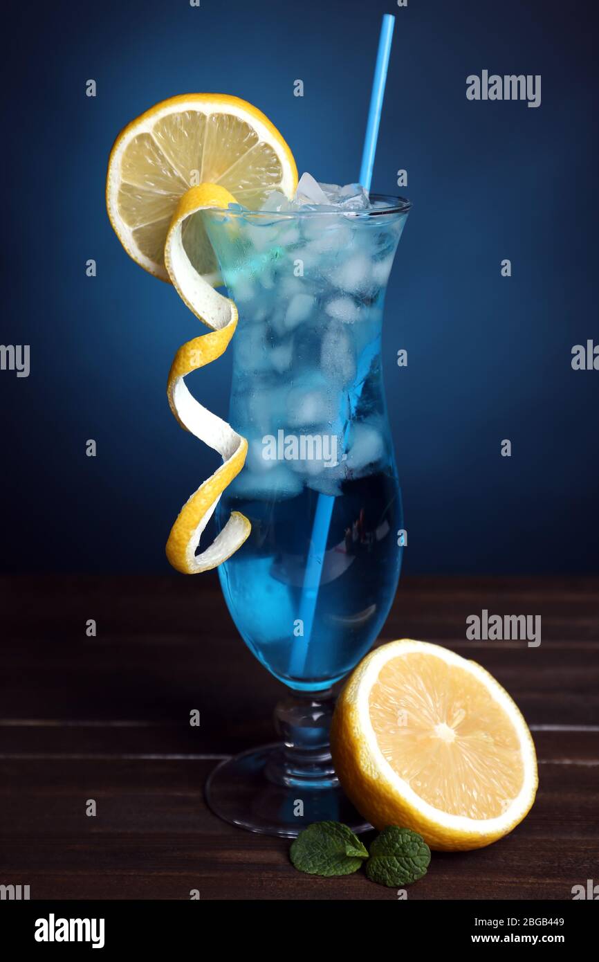 Glass of cocktail on table on dark blue background Stock Photo - Alamy