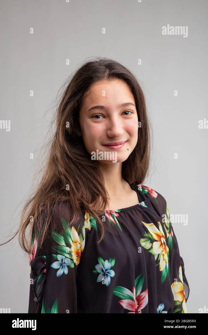 Happy friendly young woman in a floral top turning to smile at the ...
