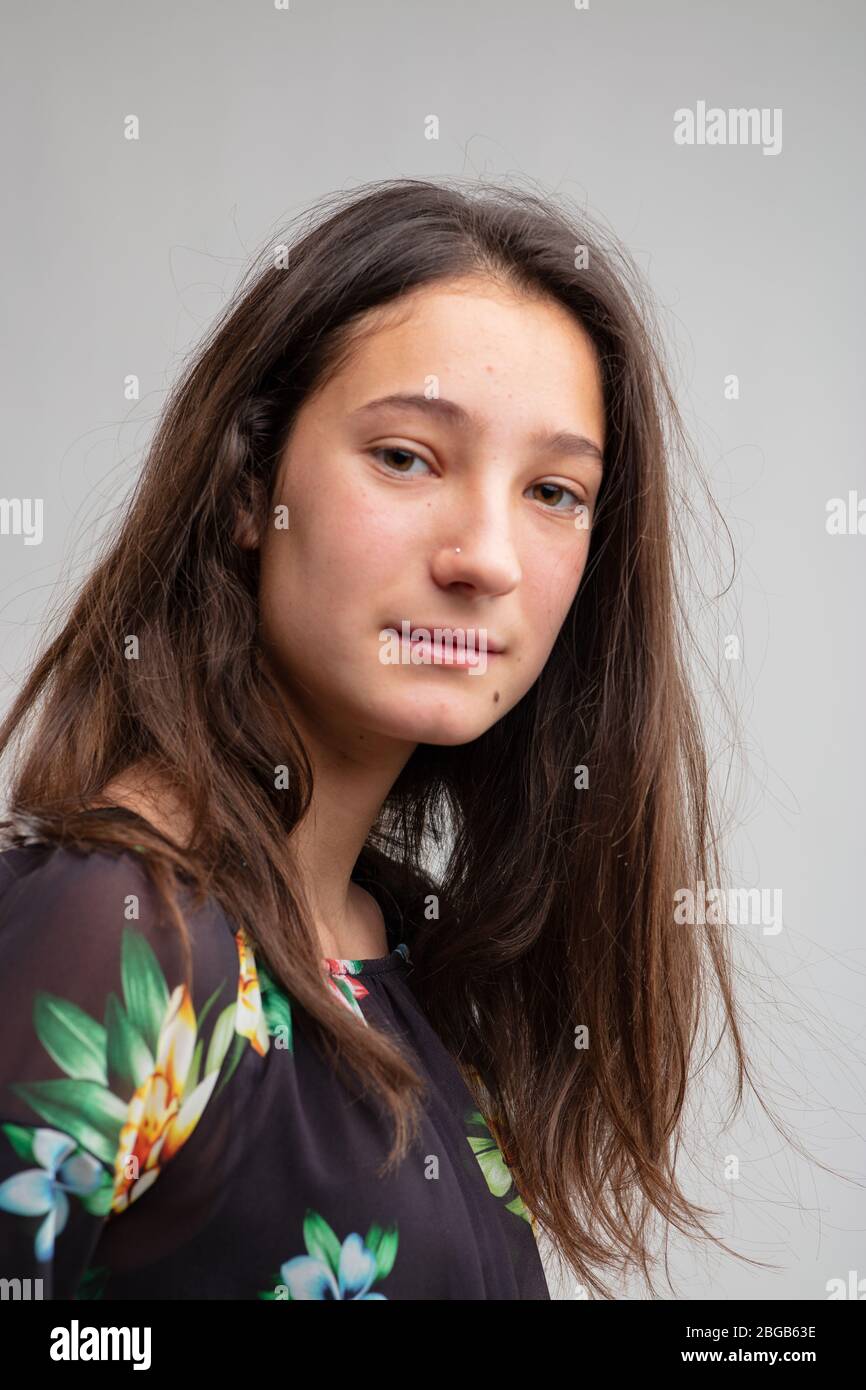 Thoughtful young woman looking quietly at camera in a half turned head ...