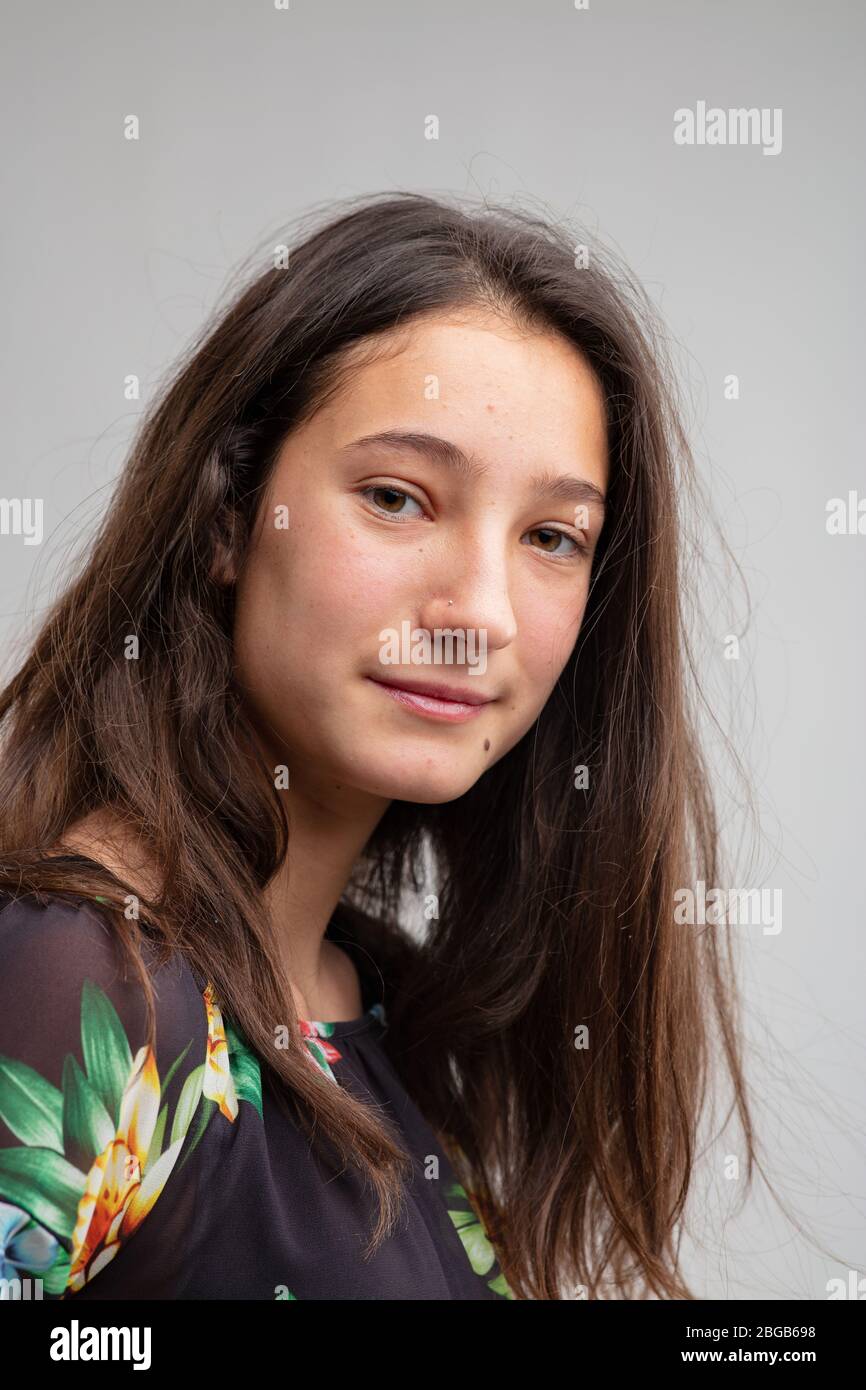 Attractive young woman with a quiet smile and long brown hair turning ...