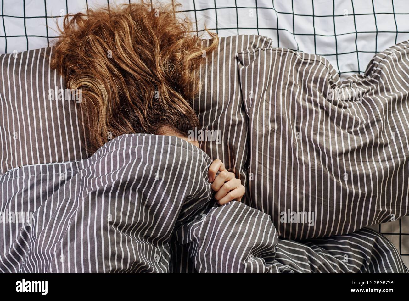 Sleeping woman covered under blanket in the bed and vintage alarm clock ...