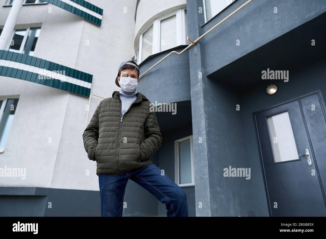 teen boy posing near wall of high-rise buildings with apartments, a ...
