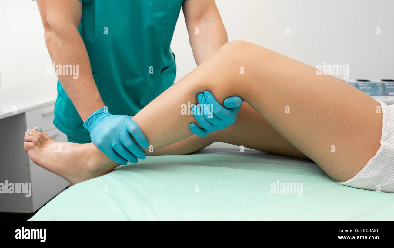 Osteopath doing a diagnosis of a woman's leg. Woman may have a broken ...
