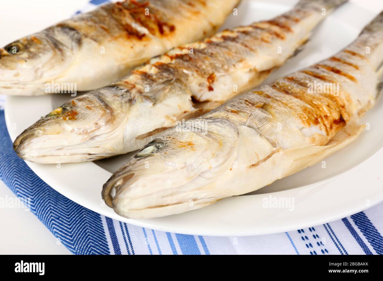 Delicious grilled fish on plate on table close-up Stock Photo - Alamy