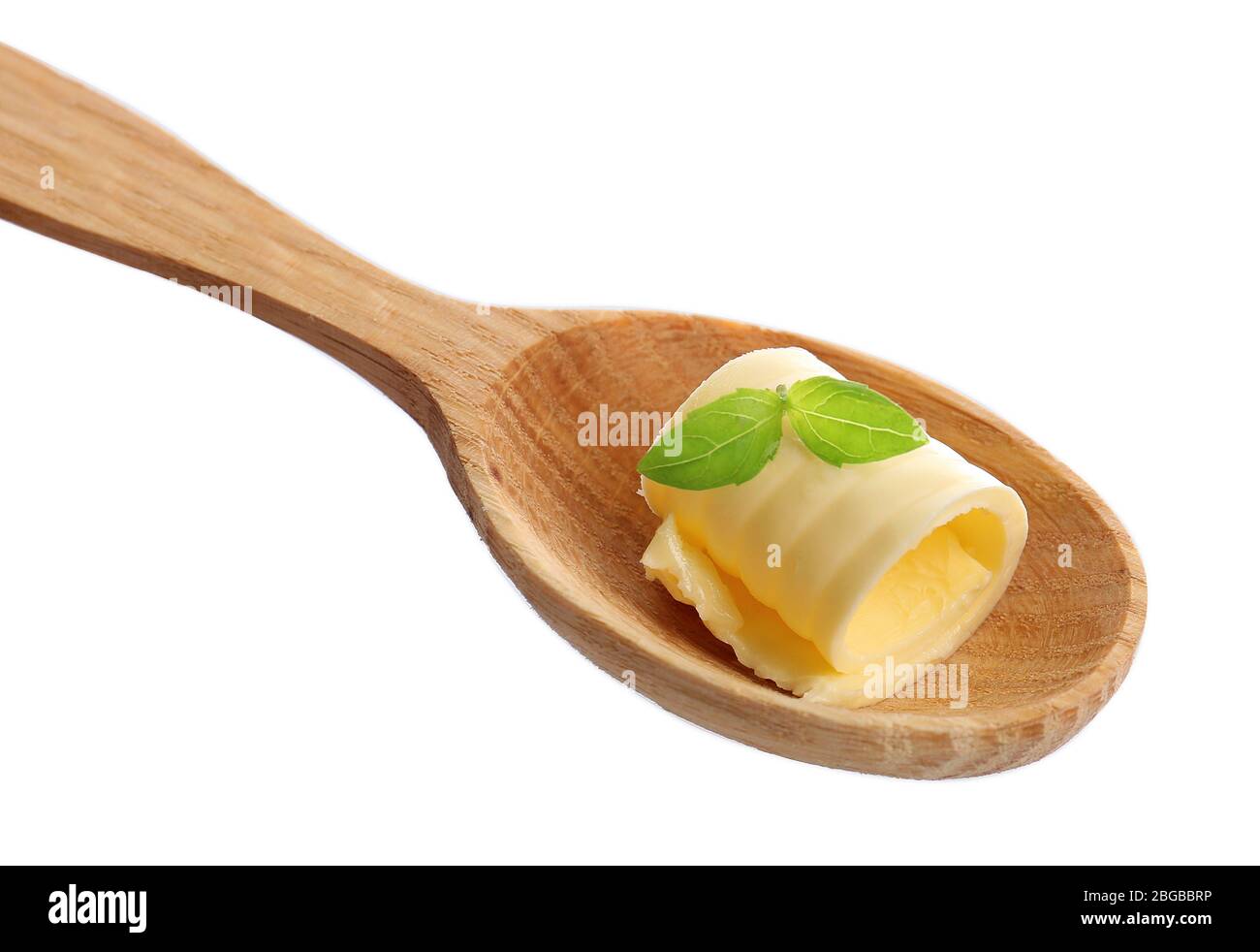 Curl of fresh butter with basil on wooden spoon, isolated on white ...