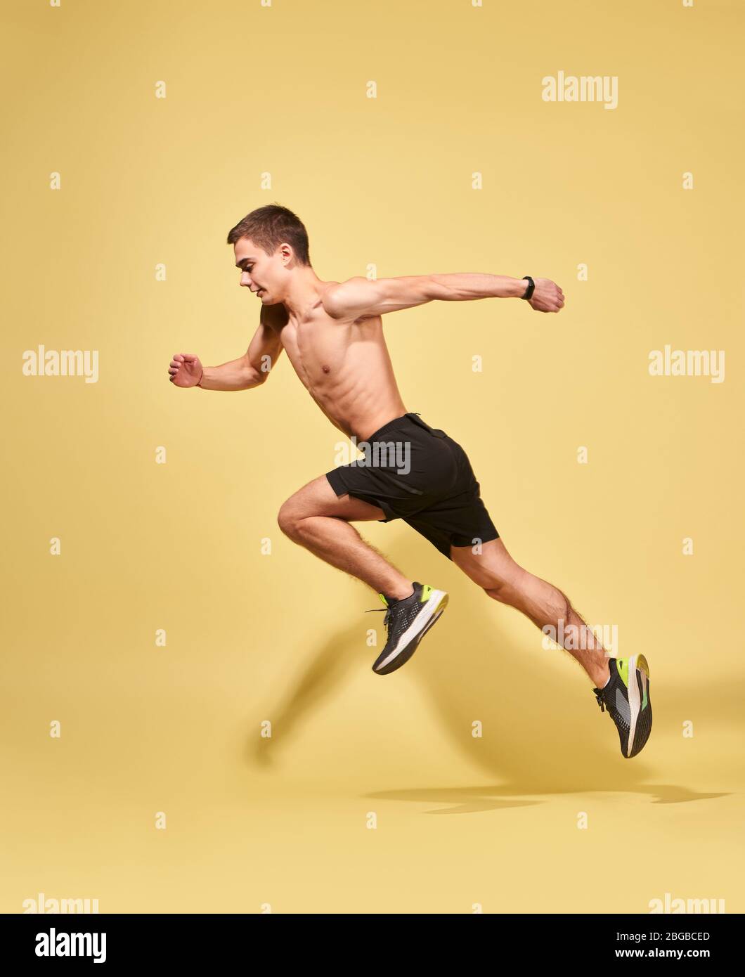 Side view of sportsman running in studio on yellow background Stock ...