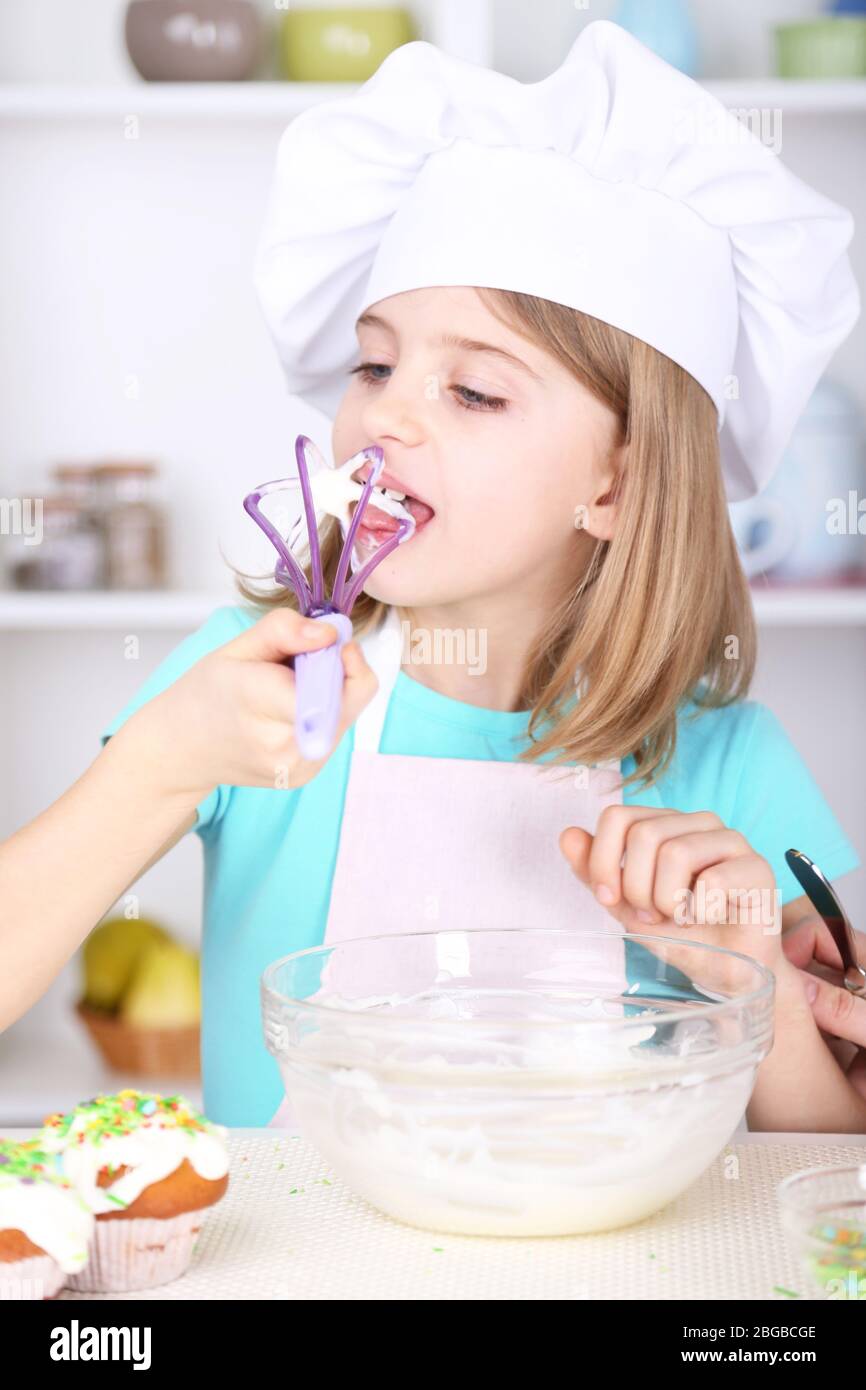 Little girl eating cream in kitchen at home Stock Photo - Alamy