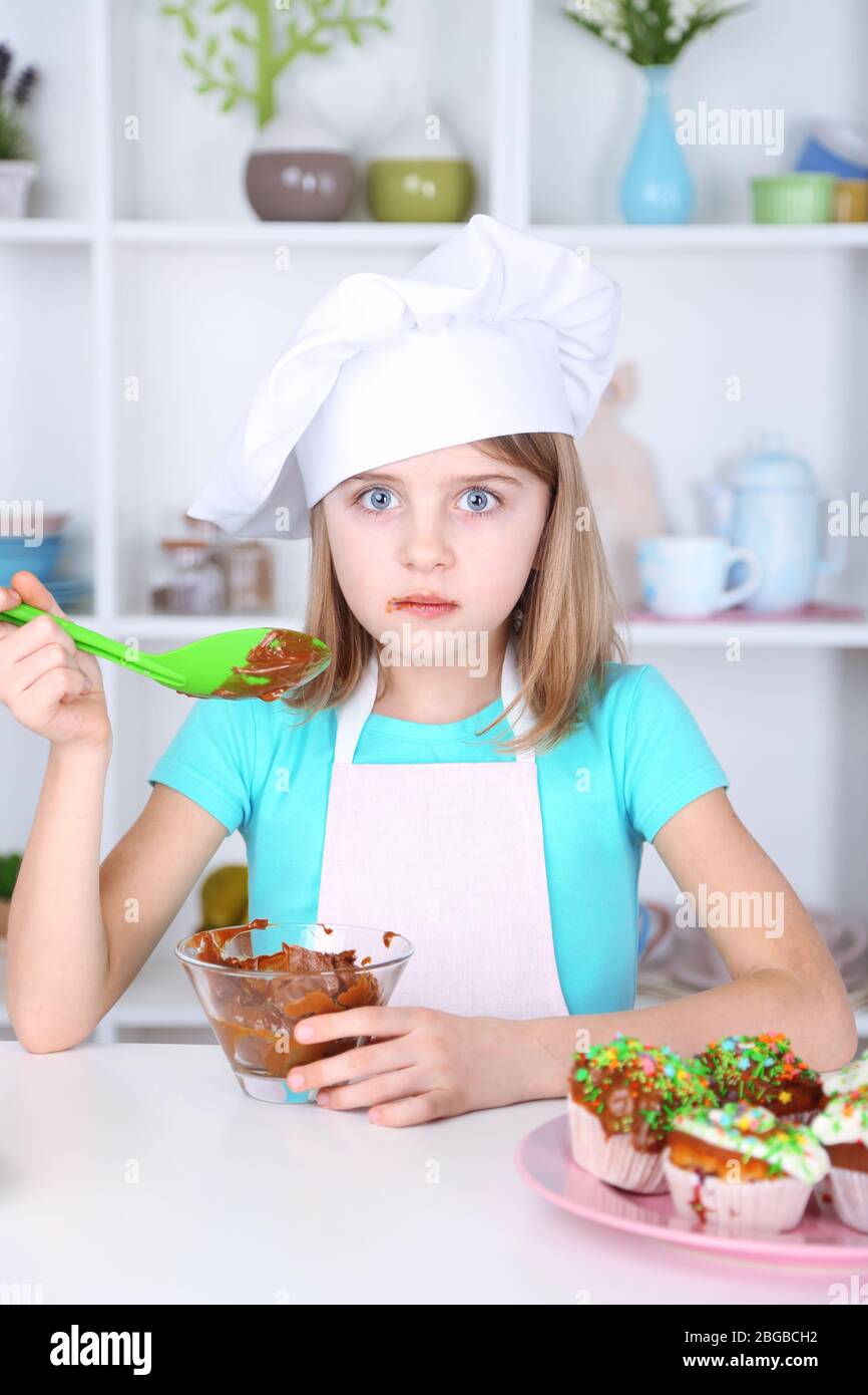 Little girl eating cream in kitchen at home Stock Photo - Alamy