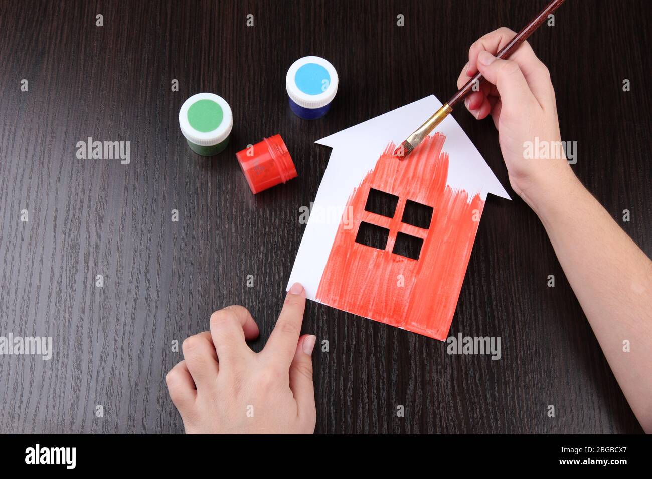 Female hand coloring paper cabin, on wooden background Stock Photo - Alamy