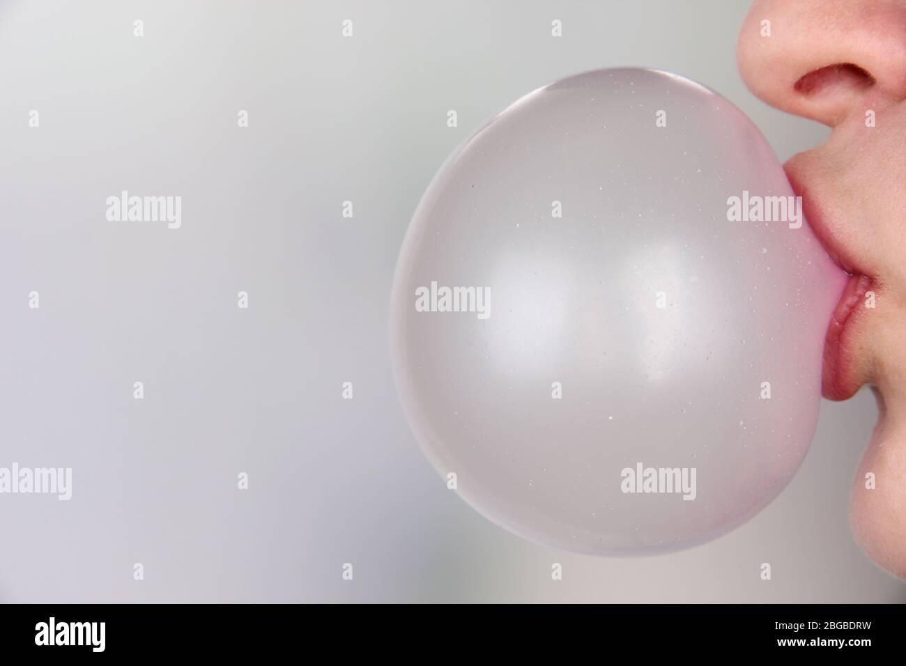 Person doing bubble with chewing gum on bright background Stock Photo ...