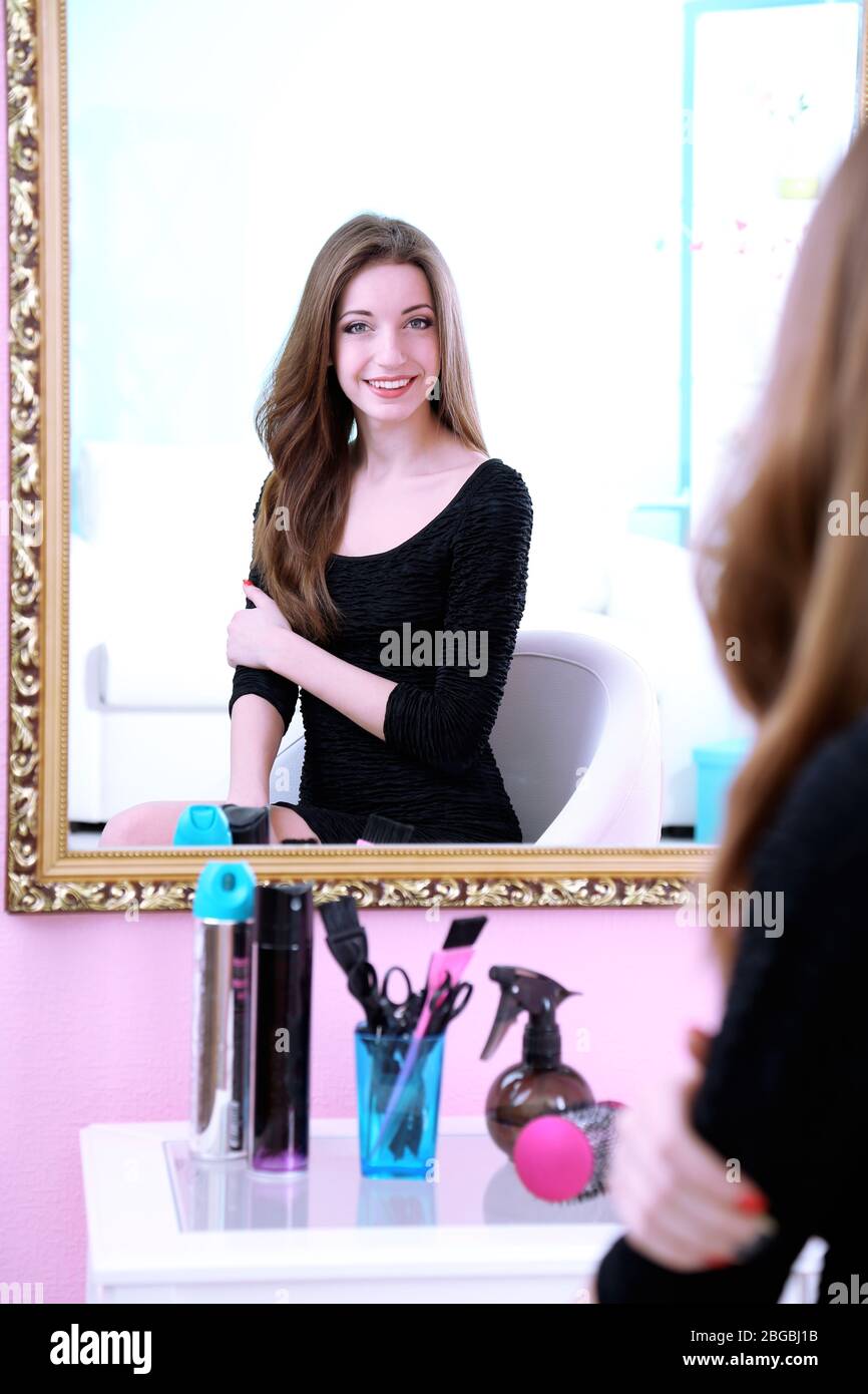 Young beautiful woman sitting front of mirror in room Stock Photo - Alamy