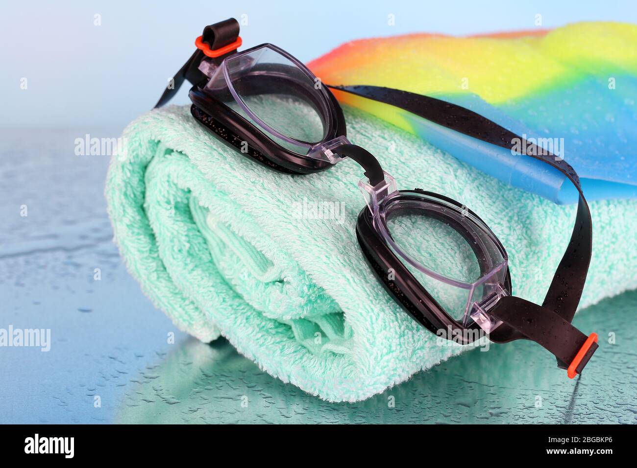 Set for pool: swim cap, goggles and towel on blue background Stock ...