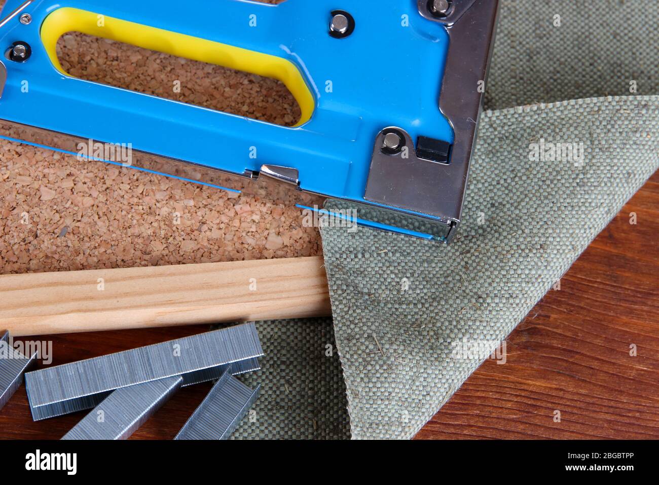 Construction stapler with staples and cork board on wooden background ...