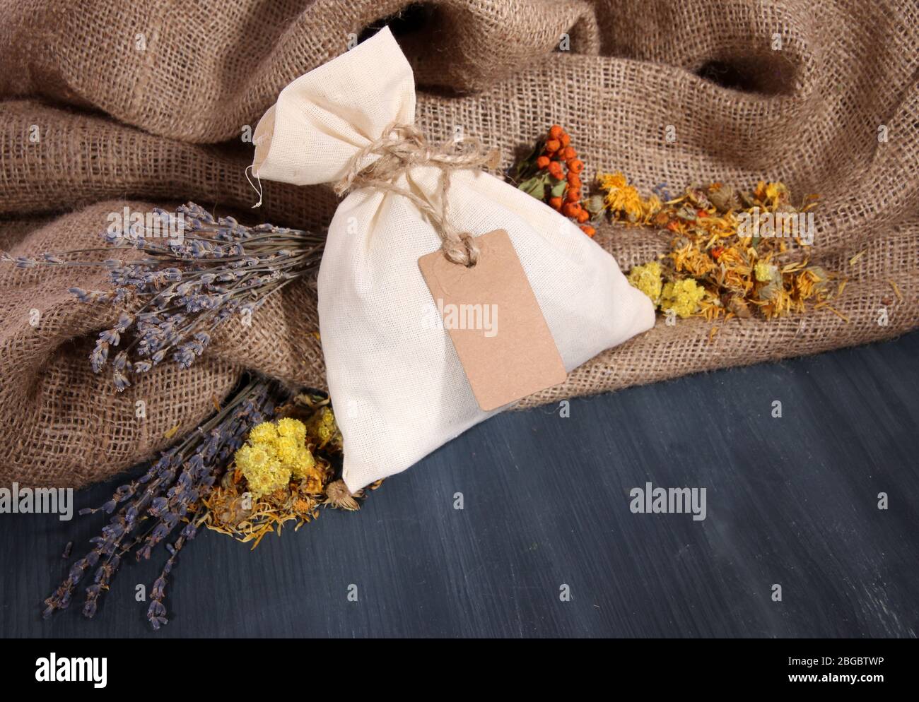 Textile sachet pouch with dried flowers, herbs and berries on wooden ...