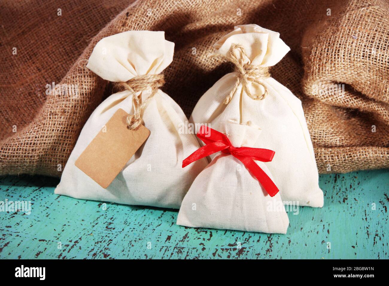 Sacks on color wooden table, on sackcloth background Stock Photo - Alamy