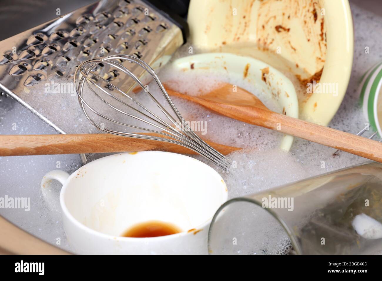 Utensils soaking in kitchen sink Stock Photo - Alamy