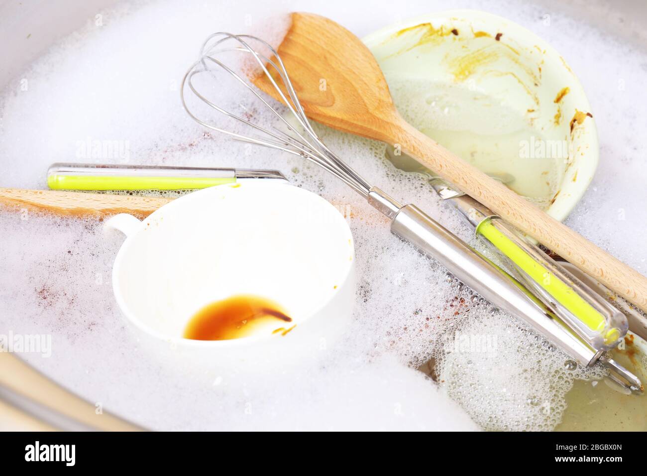 Utensils soaking in kitchen sink Stock Photo - Alamy