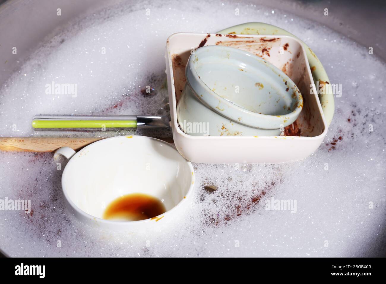 Utensils soaking in kitchen sink Stock Photo - Alamy