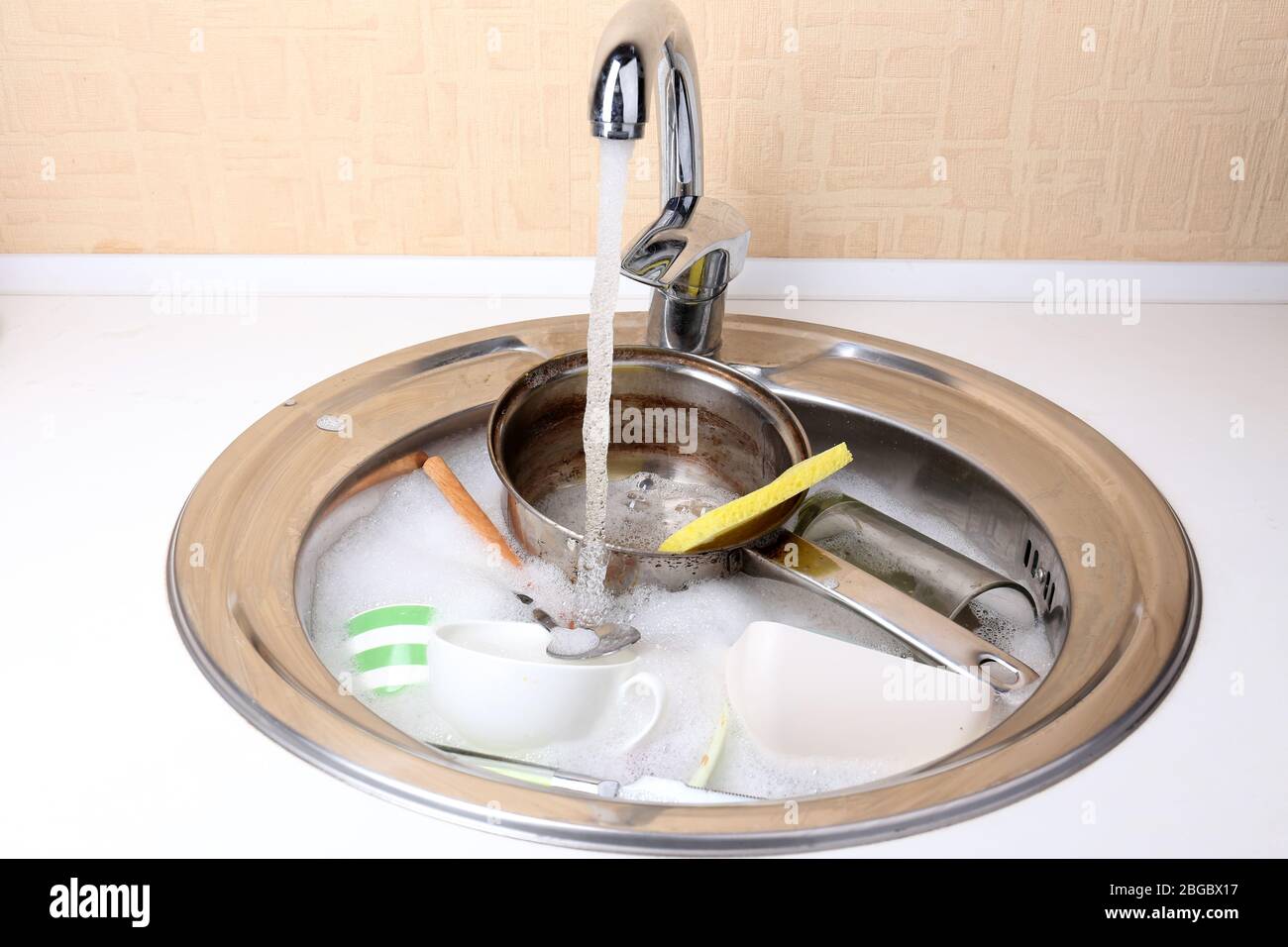Utensils soaking in kitchen sink Stock Photo - Alamy