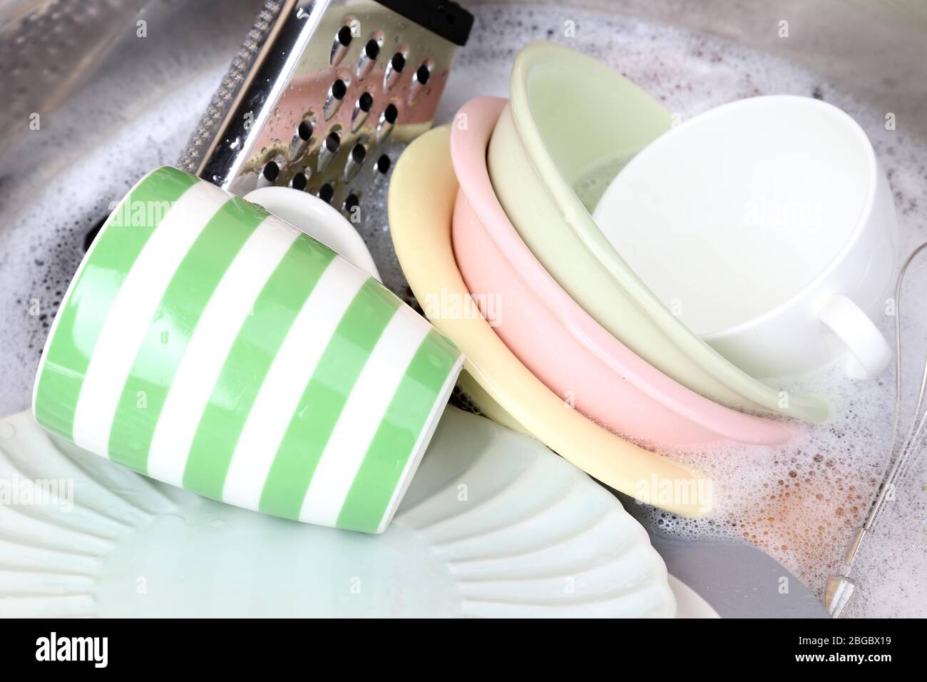 Utensils soaking in kitchen sink Stock Photo - Alamy