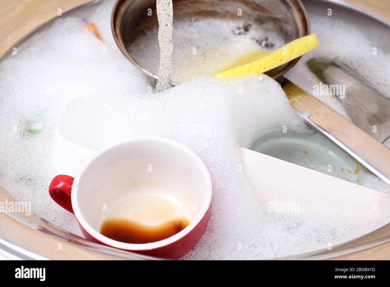 Utensils soaking in kitchen sink Stock Photo - Alamy