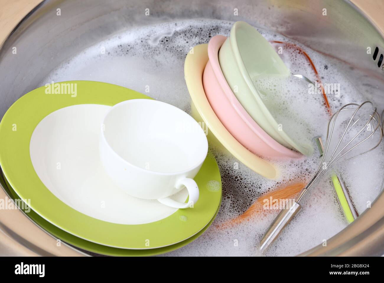 Utensils soaking in kitchen sink Stock Photo - Alamy