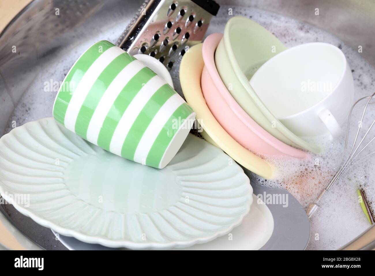 Utensils soaking in kitchen sink Stock Photo - Alamy