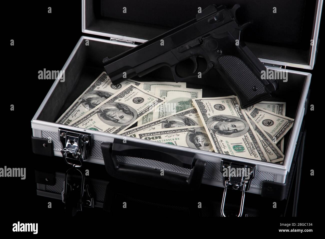 Case with money and gun, isolated on black Stock Photo - Alamy