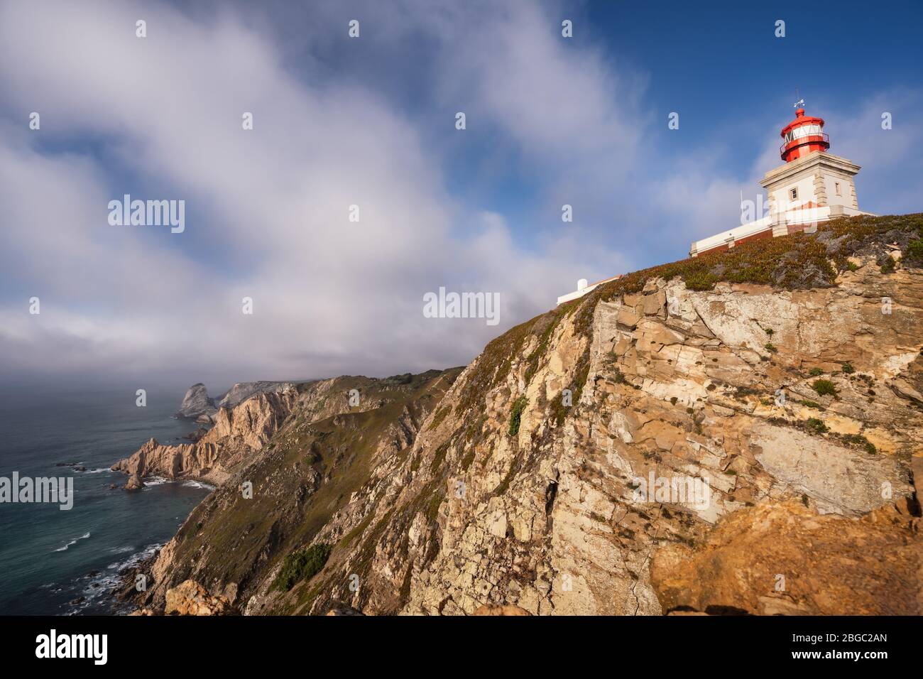 Cabo da Roca Lighthouse at cliff edge in evening sunlight against ...