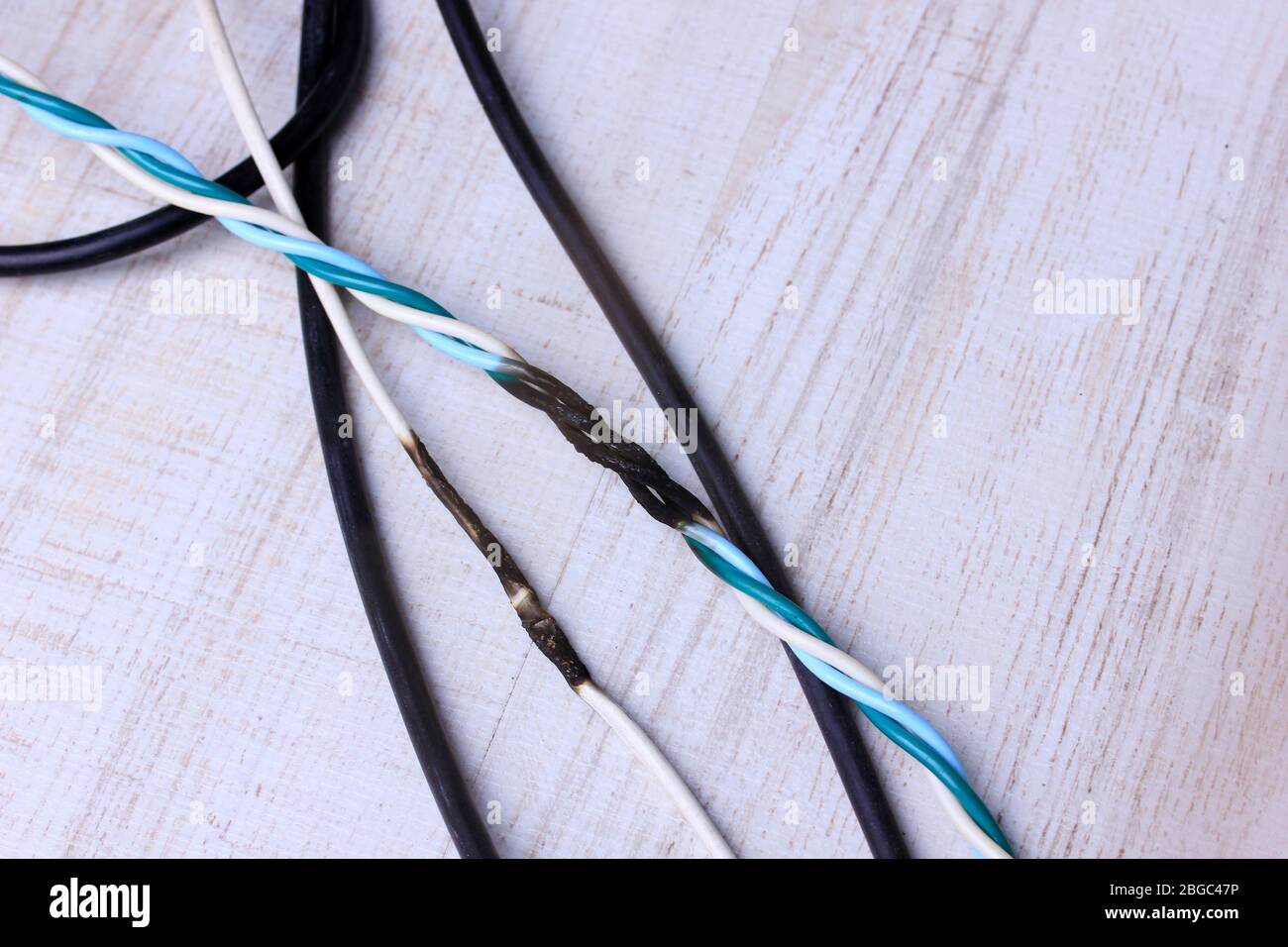 Short circuit, burnt cable, on color wooden background Stock Photo - Alamy