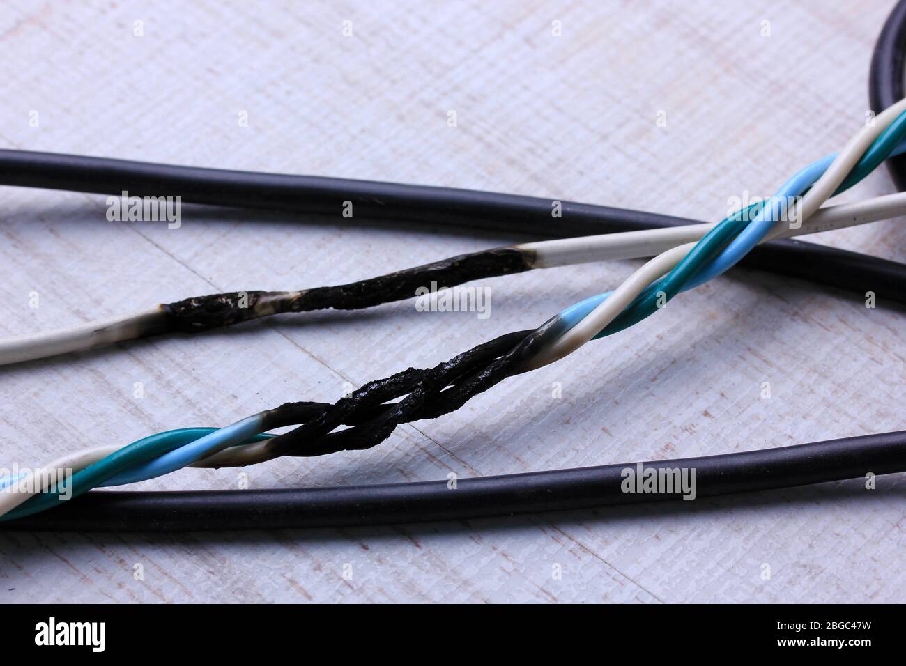 Short circuit, burnt cable, on color wooden background Stock Photo - Alamy
