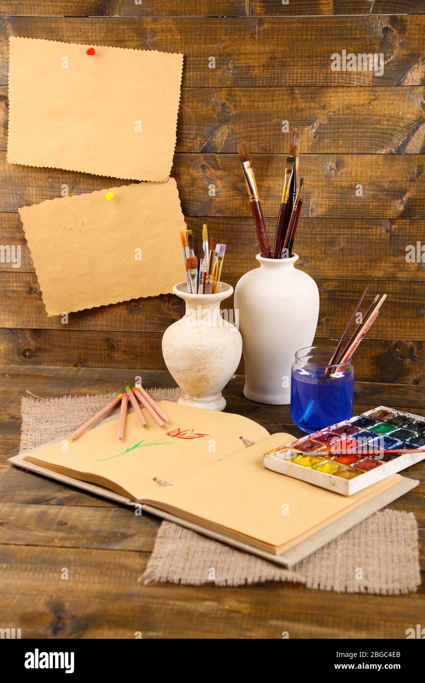 Composition with colorful watercolors, brushes in vase and sketcher on ...