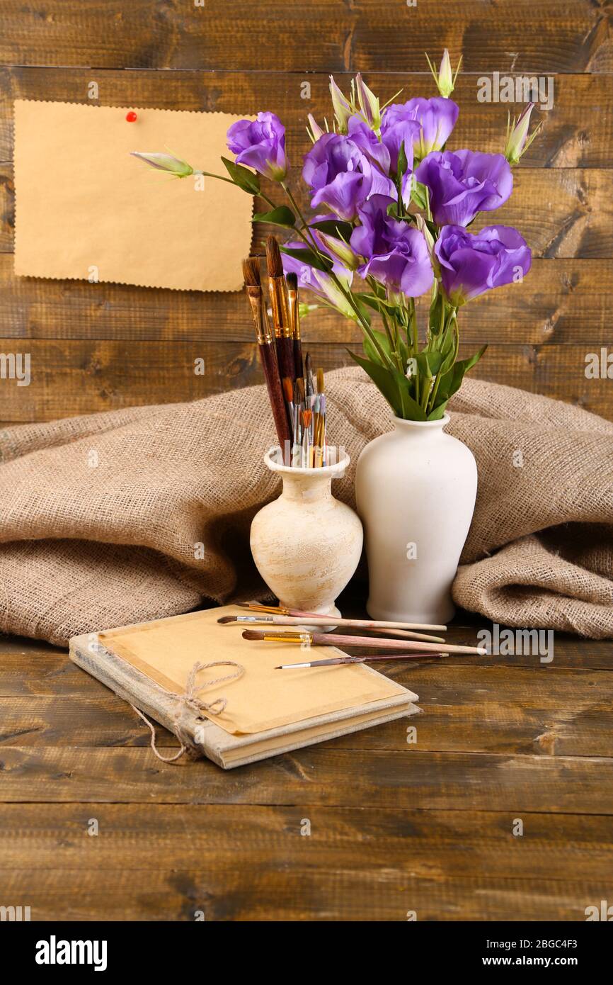 Composition with colorful watercolors, brushes in vase and sketcher on ...