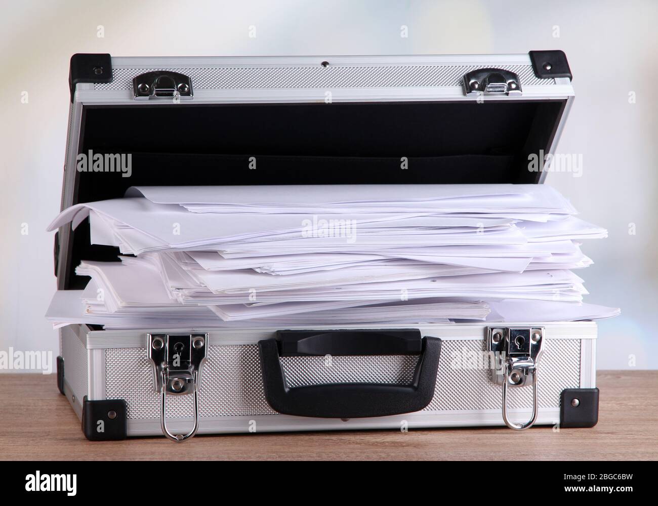 Briefcase full of papers, on wooden table, on light background Stock ...