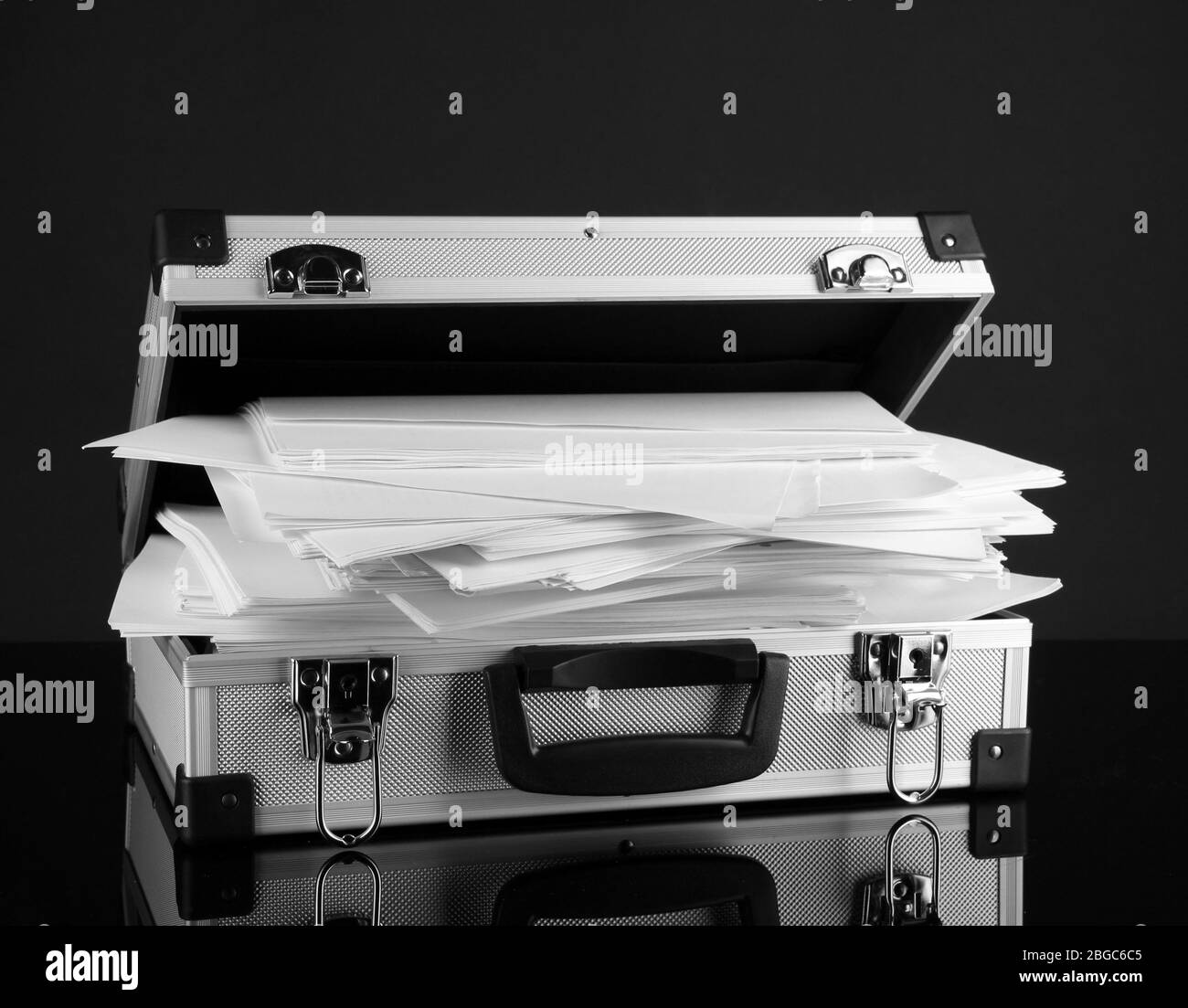 Briefcase full of papers, isolated on black Stock Photo - Alamy