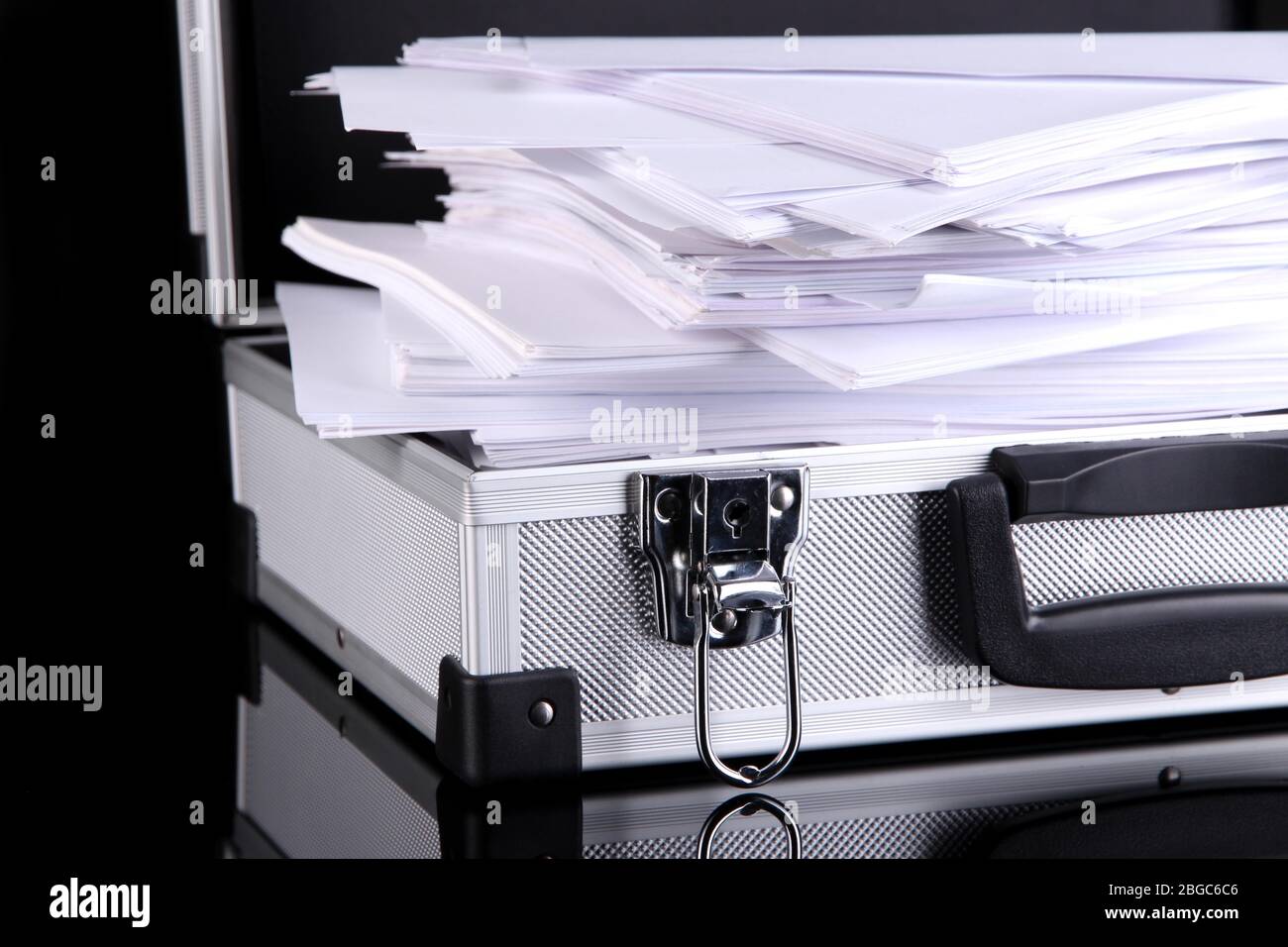 Briefcase full of papers, isolated on black Stock Photo - Alamy