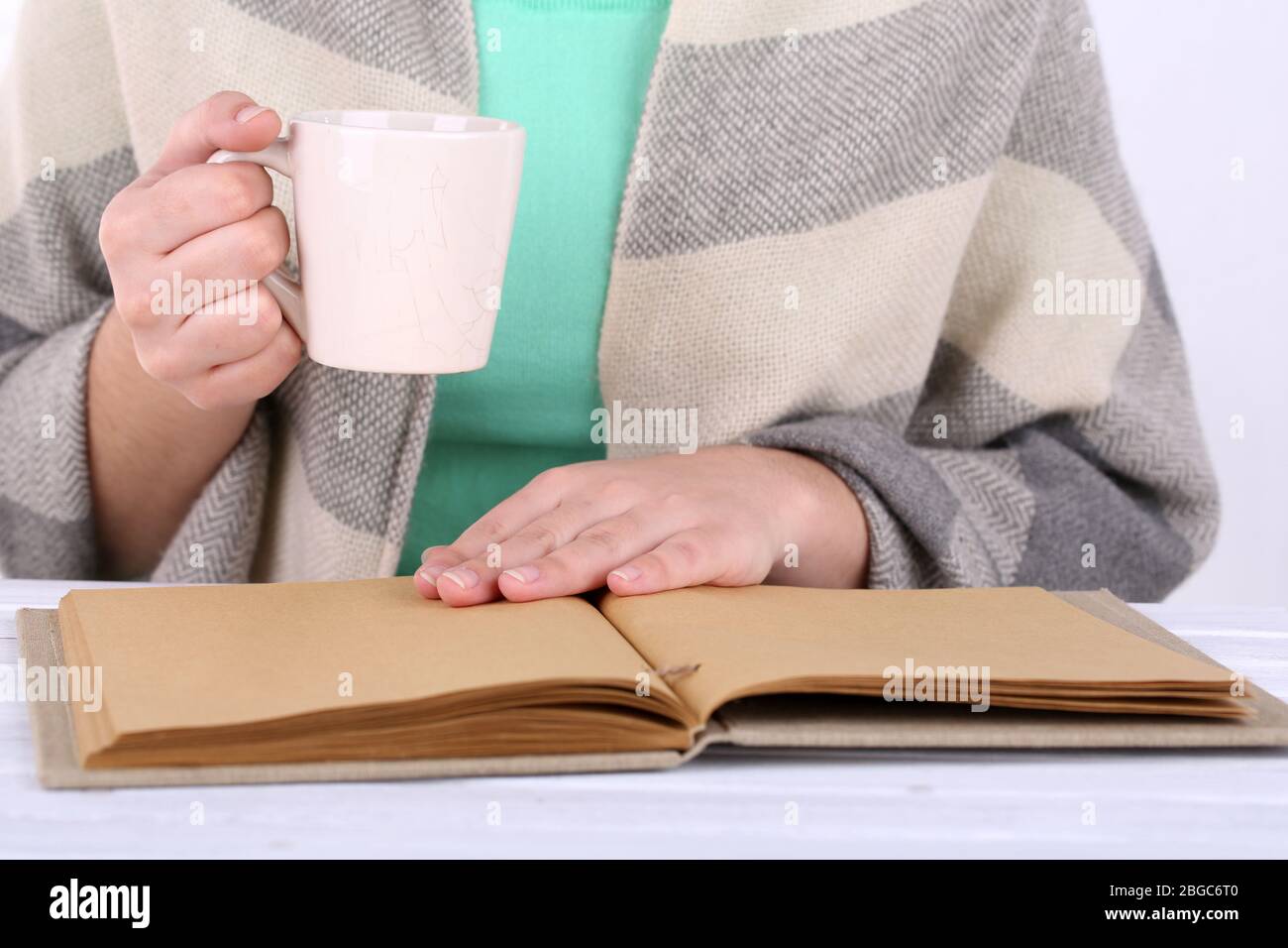 Woman reading book and drink coffee or tea, close-up Stock Photo - Alamy