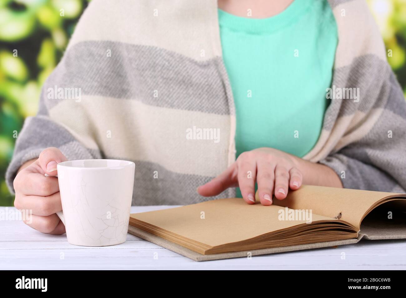 Woman reading book and drink coffee or tea, close-up Stock Photo - Alamy