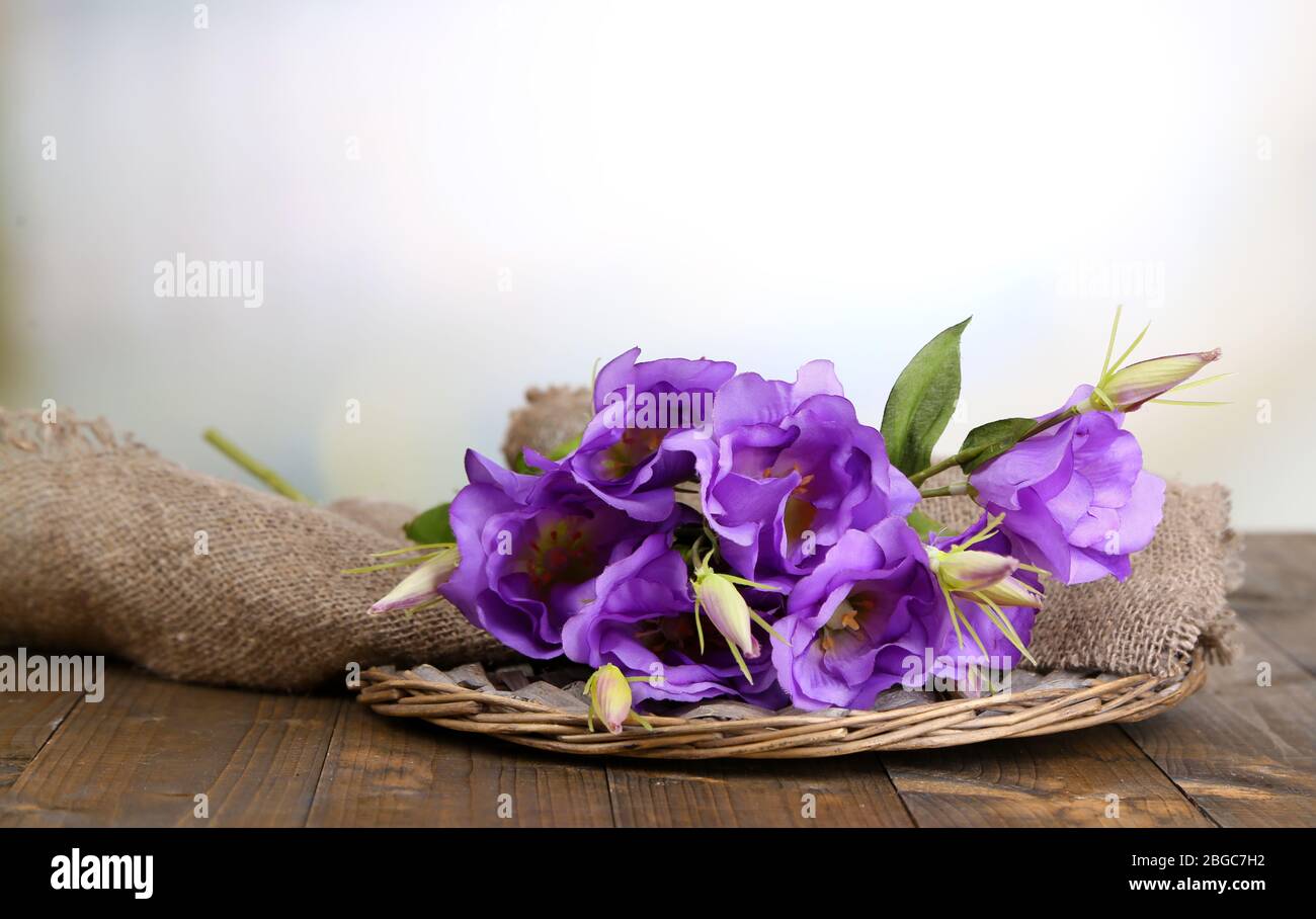 Purple artificial eustoma on sackcloth on color wooden table, on bright ...