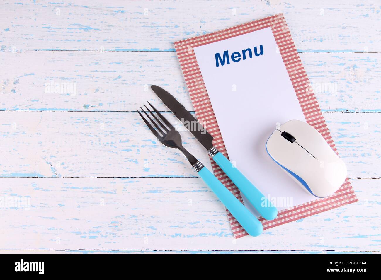 Computer mouse with menu and cutlery on wooden background Stock Photo ...