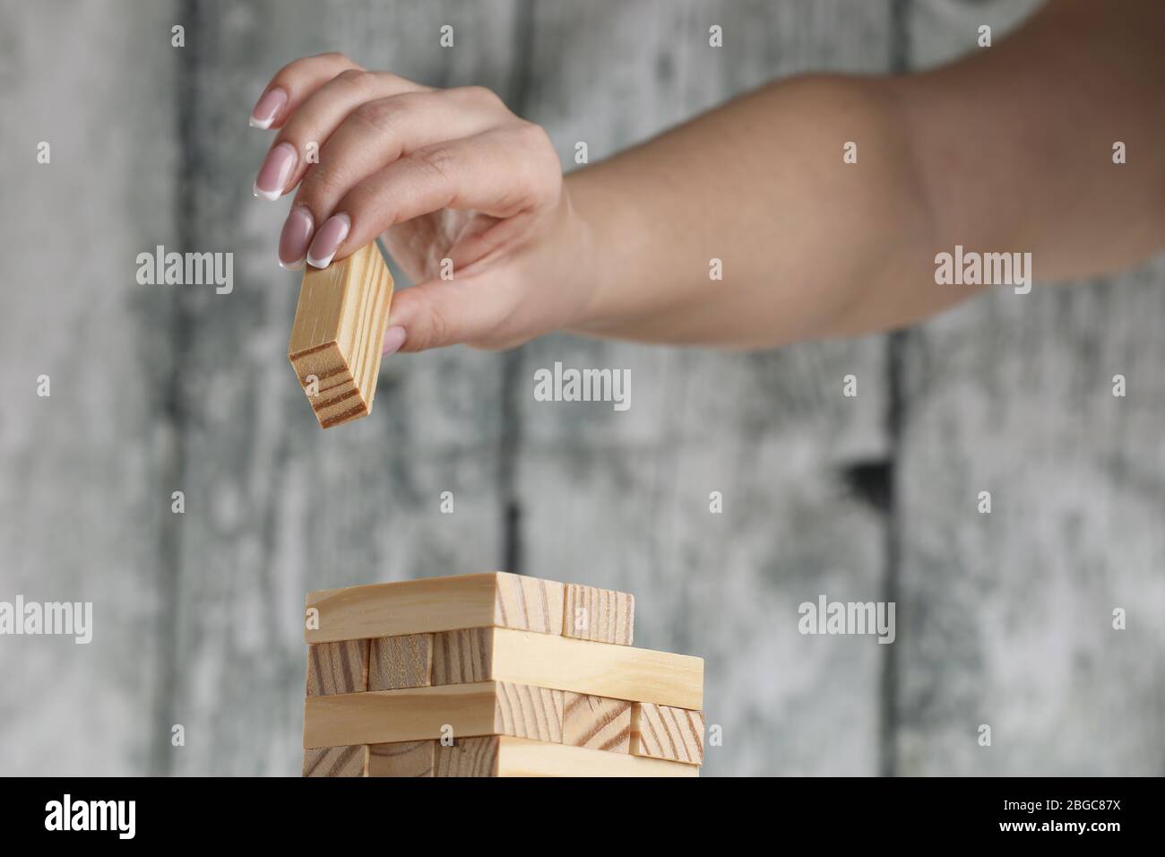 Girl hand putting wooden bricks on a table. Tower construction game ...