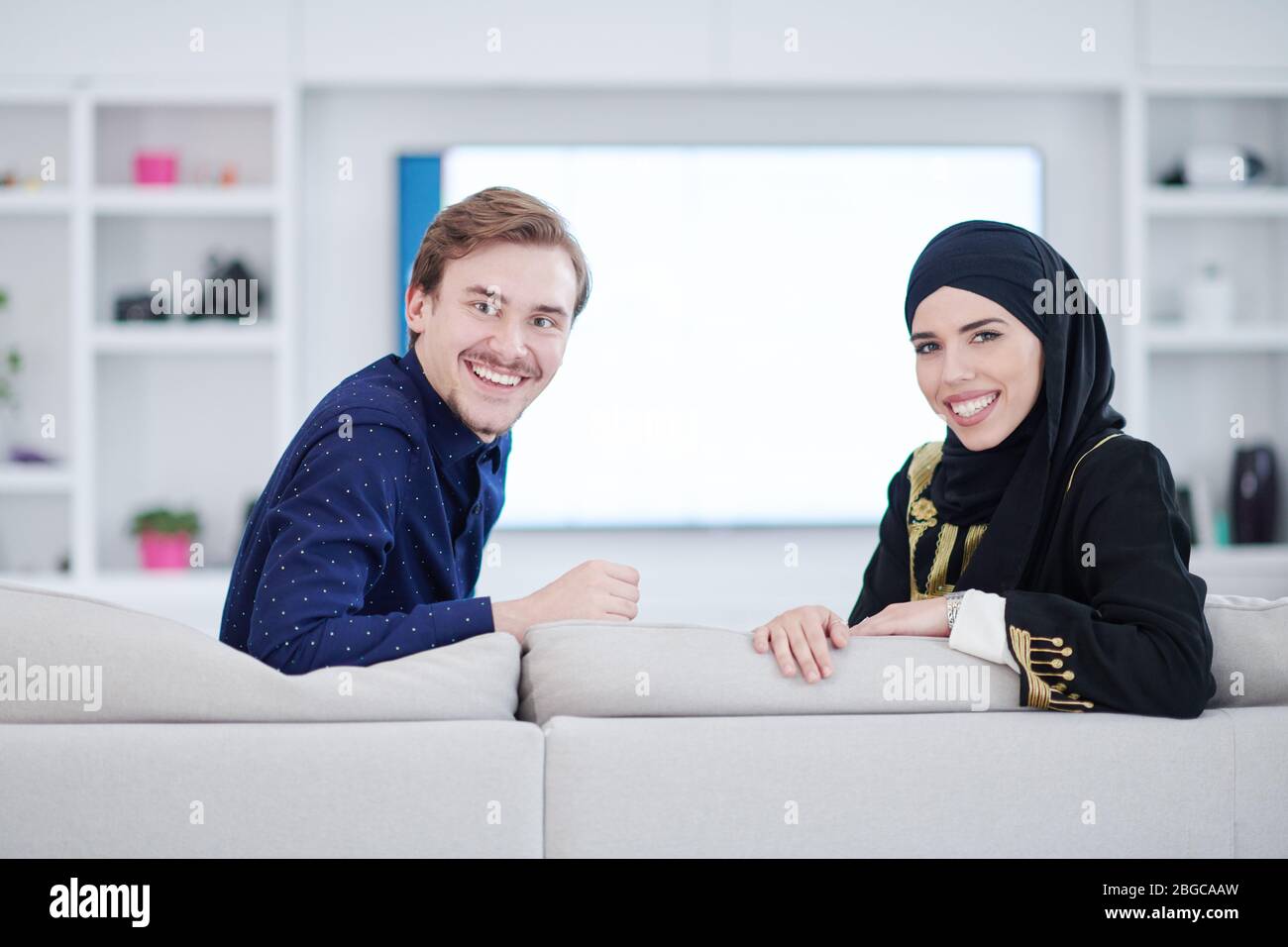young muslim couple woman wearing islamic hijab clothes sitting on sofa ...