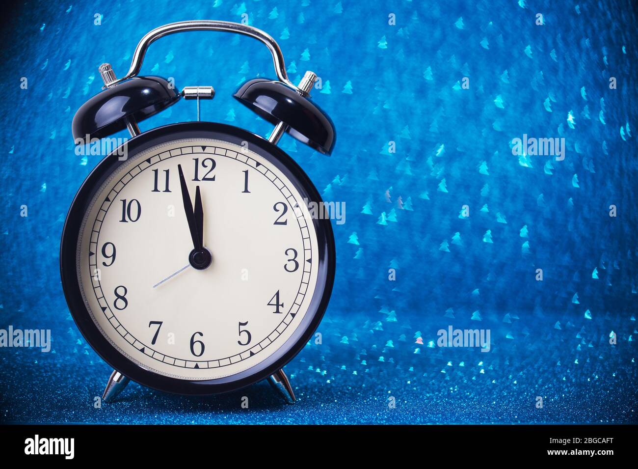 Alarm clock on a blue glitter background. Bokeh in a shape of christmas ...