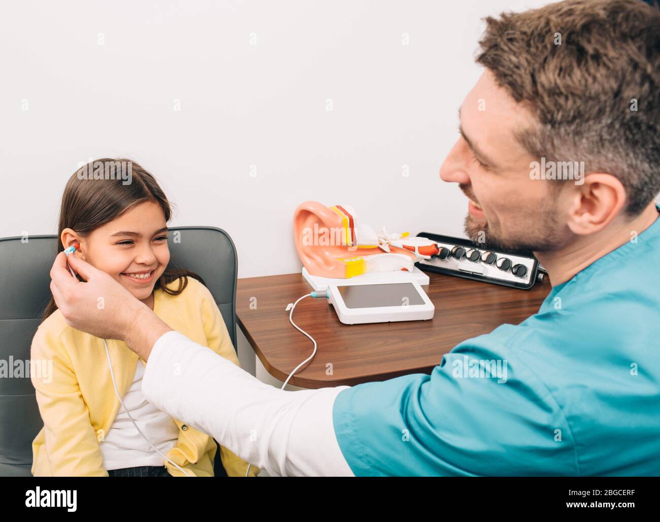 Audiologist check a child's ears.Mixed race girl having hearing test ...