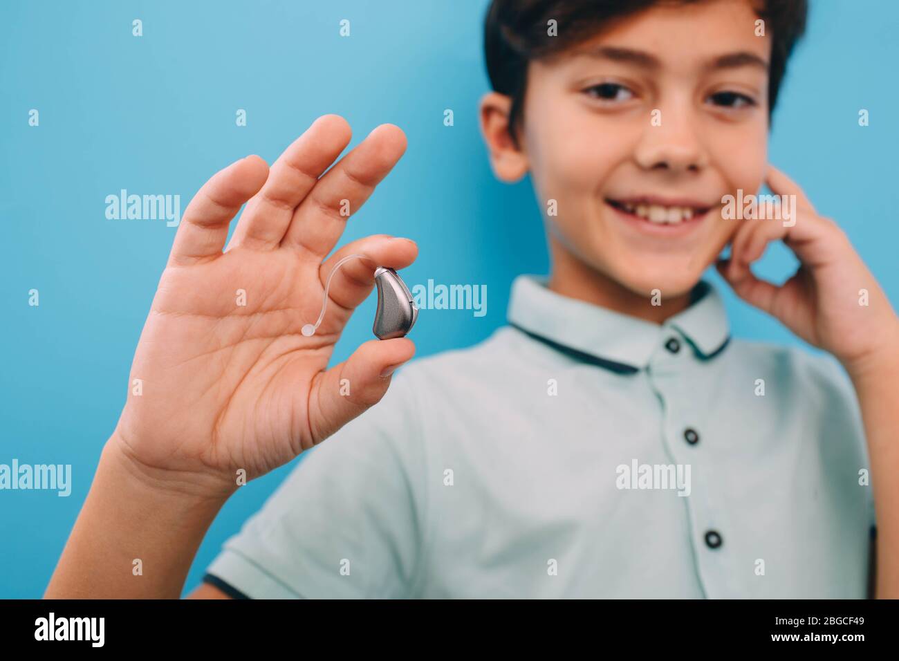 advertising hearing aid for children, a mixed race boy shows a hearing ...