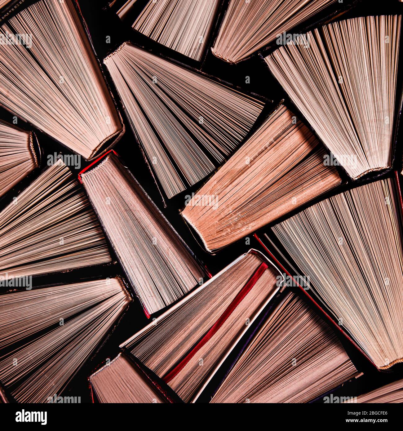 Many old multi-colored open books stand on the bookshelf in the library ...