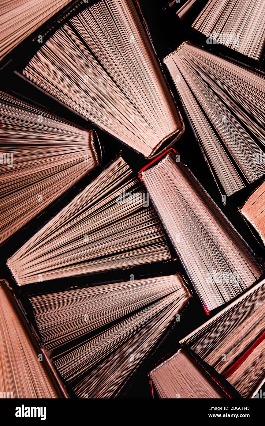 Many old multi-colored open books stand on the bookshelf in the library ...
