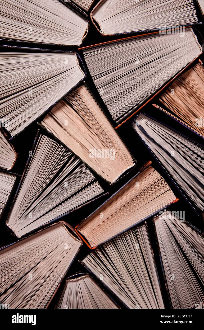 Many old multi-colored open books stand on the bookshelf in the library ...